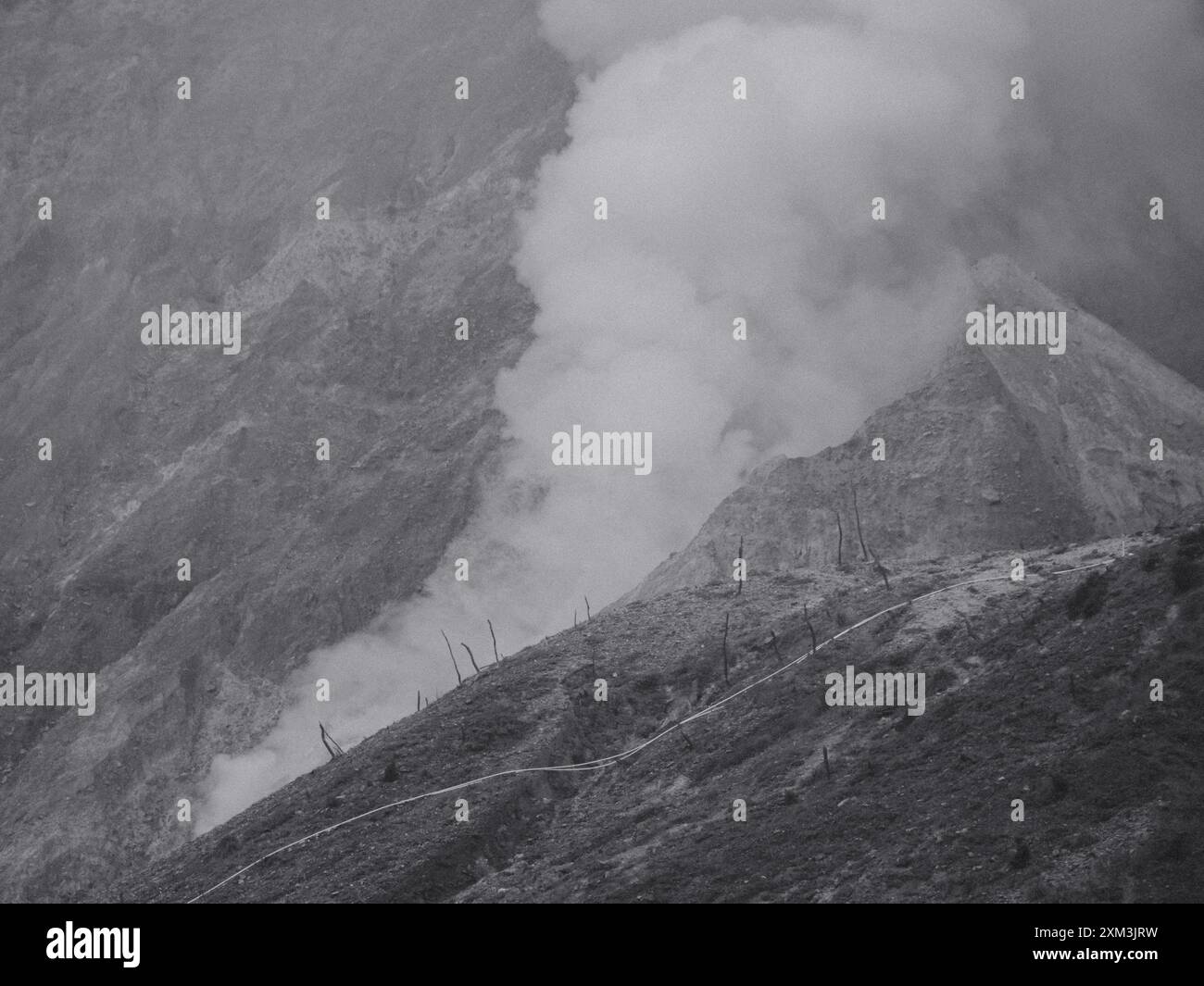 A mountain with a cloud of smoke rising from it. The smoke is dark and ...