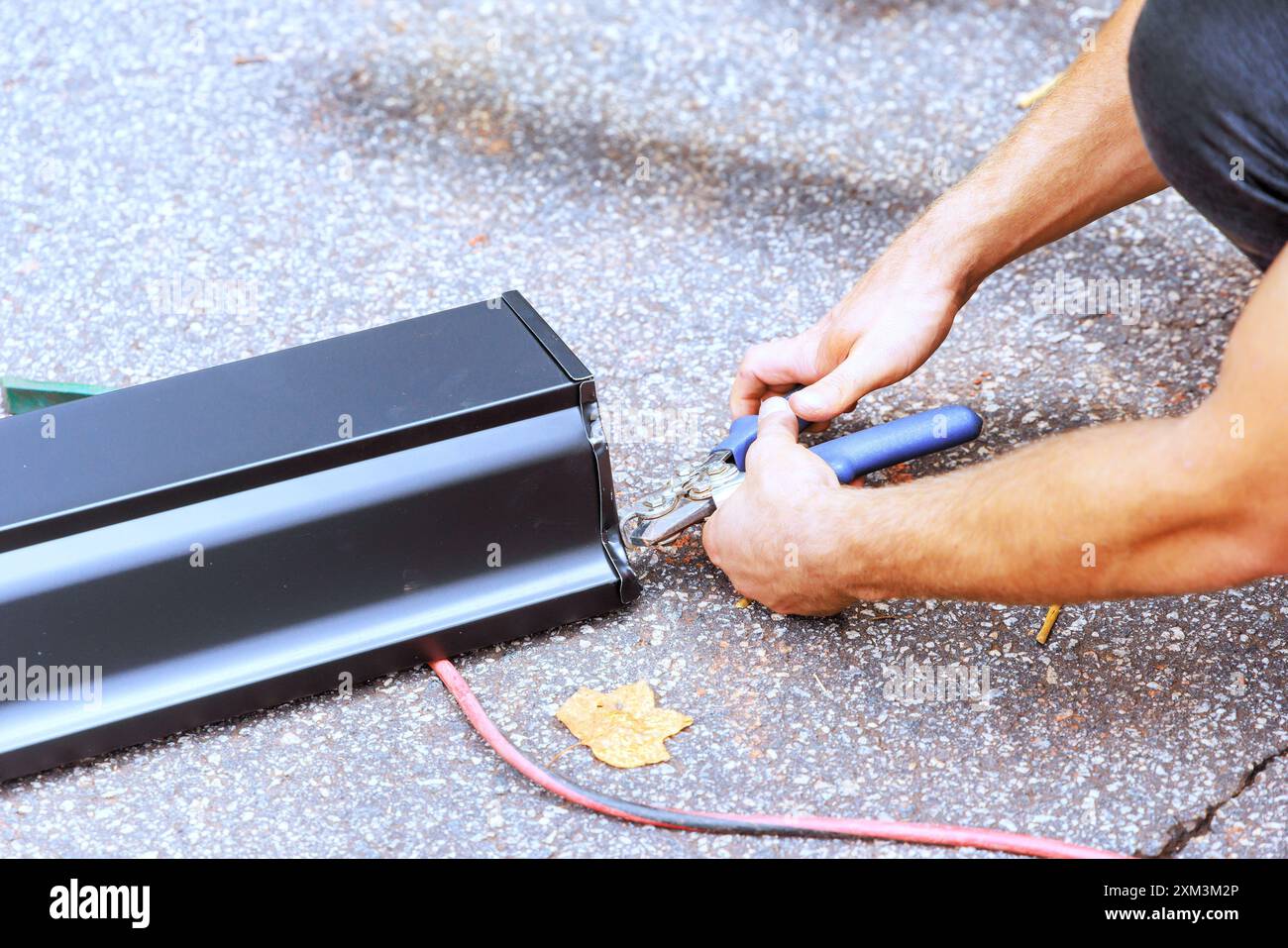 Worker cutting aluminum rain gutter with shears after bending at ...