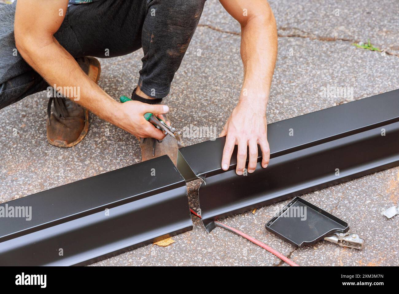 After bending aluminum rain gutters on machine tool, worker cuts them ...