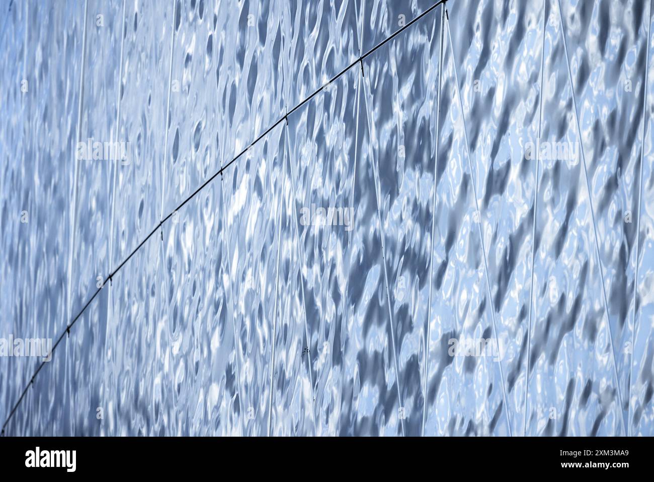 Shiny blue metal wall structure made of rippled stainless steel plates ...