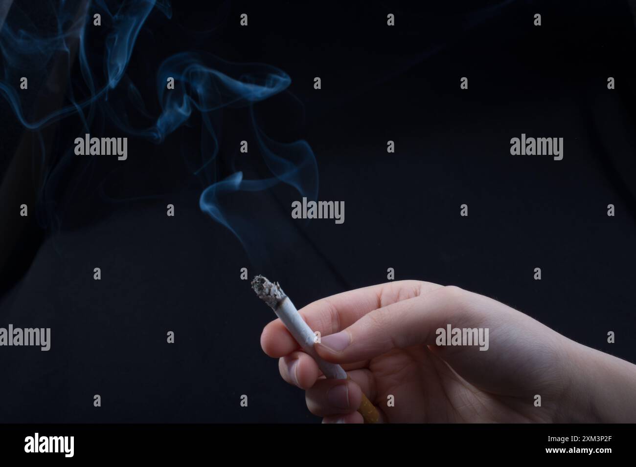 Hand is holding smoking cigarette with smoke around Stock Photo - Alamy