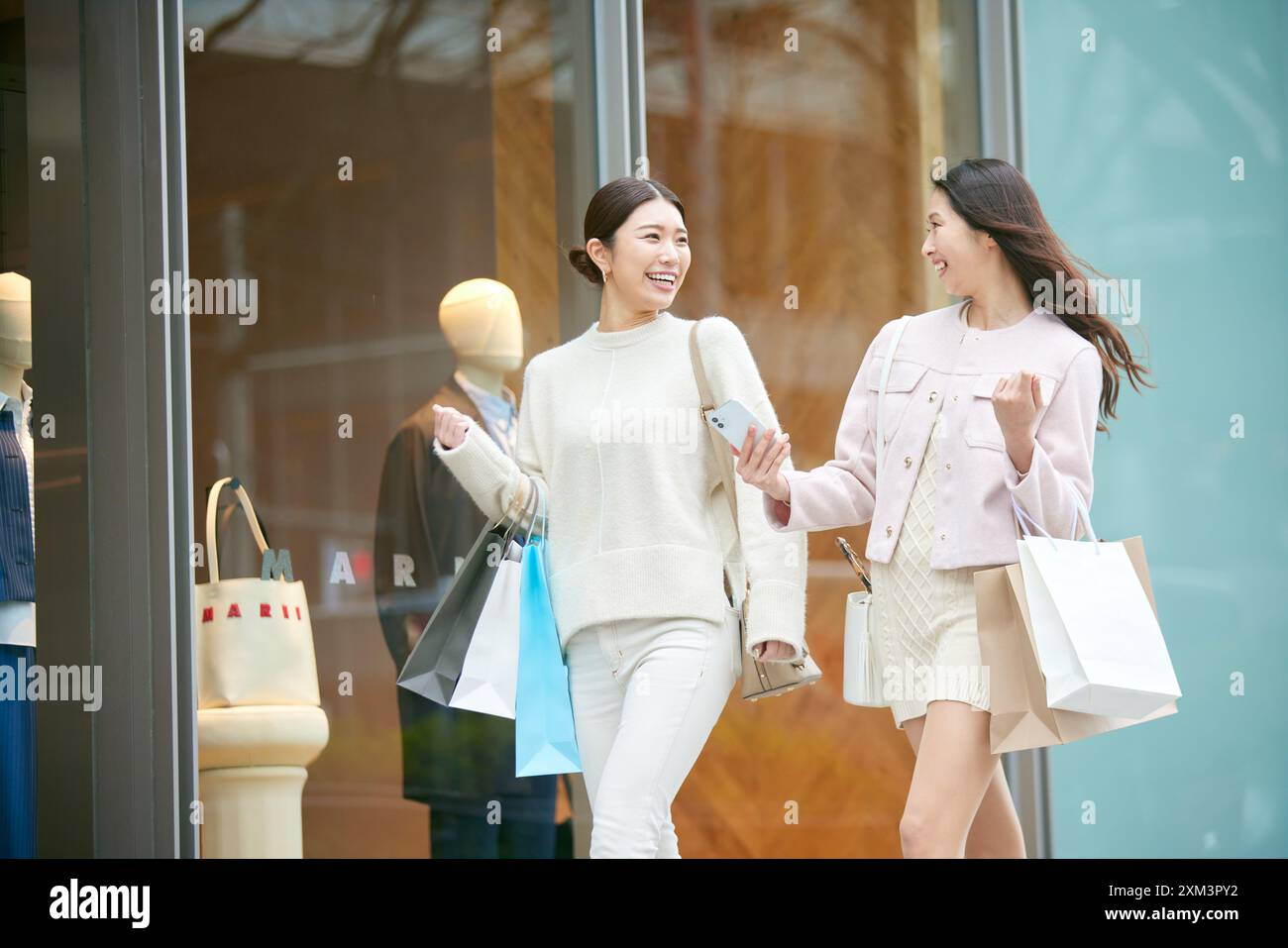 Two Women Walking In Front Of A Store Window Stock Photo - Alamy