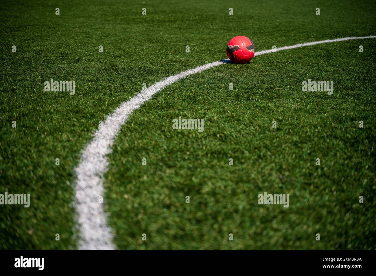 A soccer ball lies on the ground in a green field in natural light ...