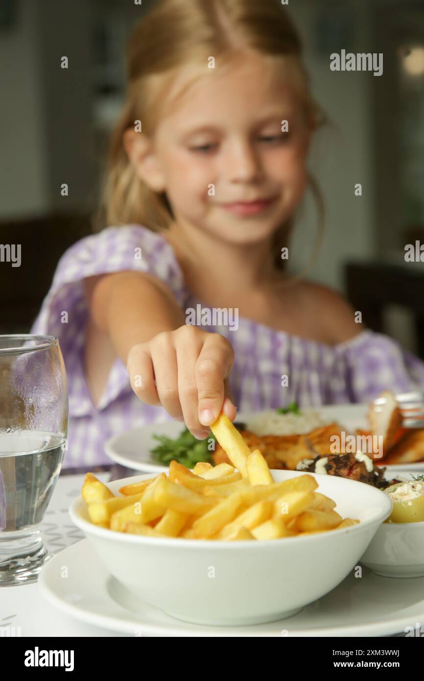 Little girl is eating french fries Stock Photo - Alamy