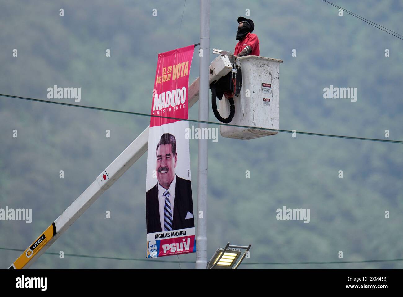 A worker hangs an election campaign poster of Venezuelan President ...