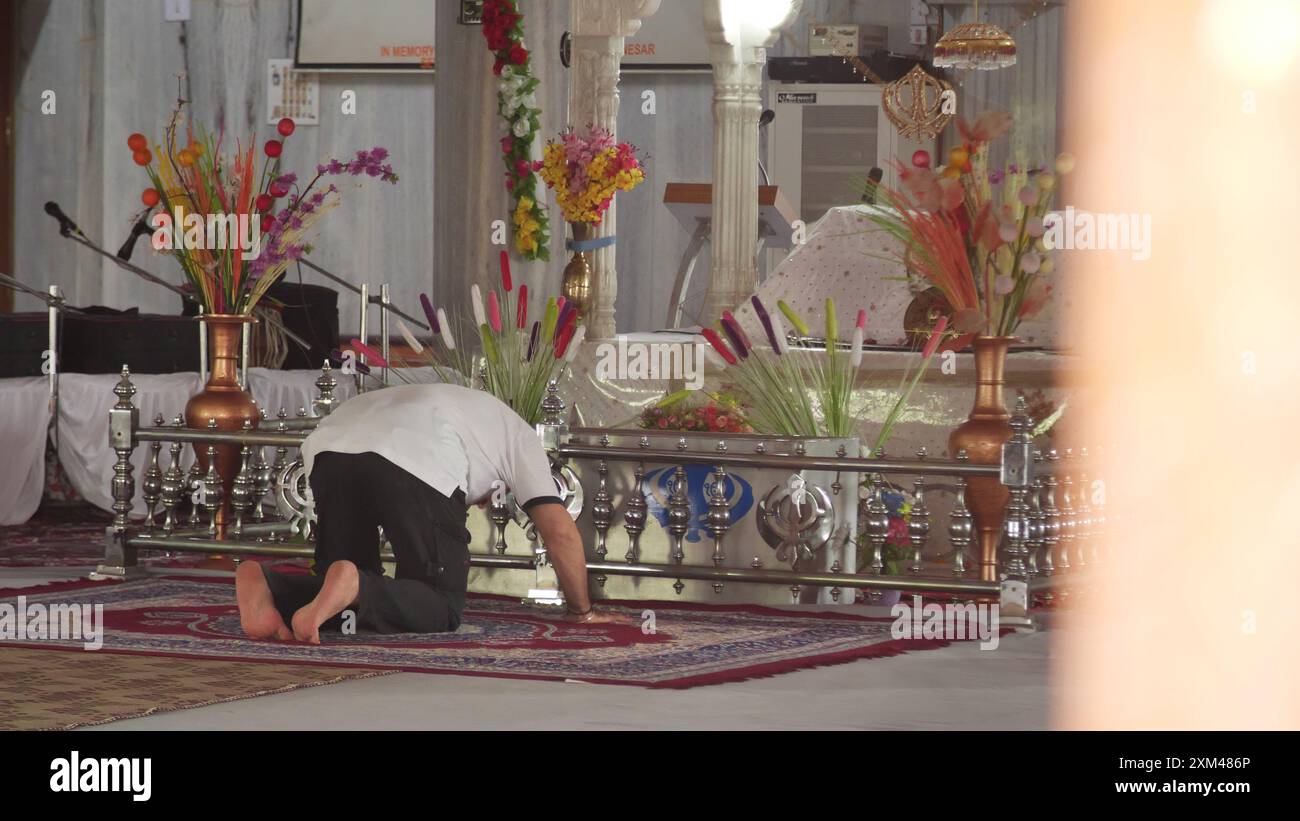 A person bowing in prayer inside a temple adorned with flowers and ...