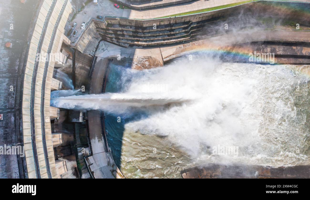 Aerial view of dam releasing water creating powerful spray and rainbow ...