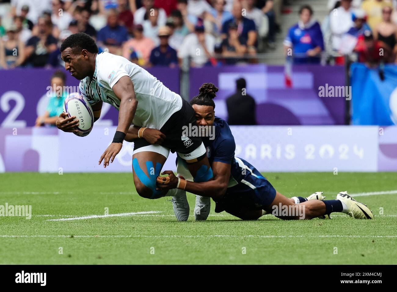 Paris, France, 25 July, 2024. Joji Nasova (1) of Team Fiji is tackled ...