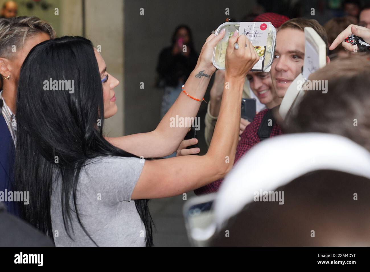 Katy Perry signs an autograph on a fan's Waitrose ready meal as she ...