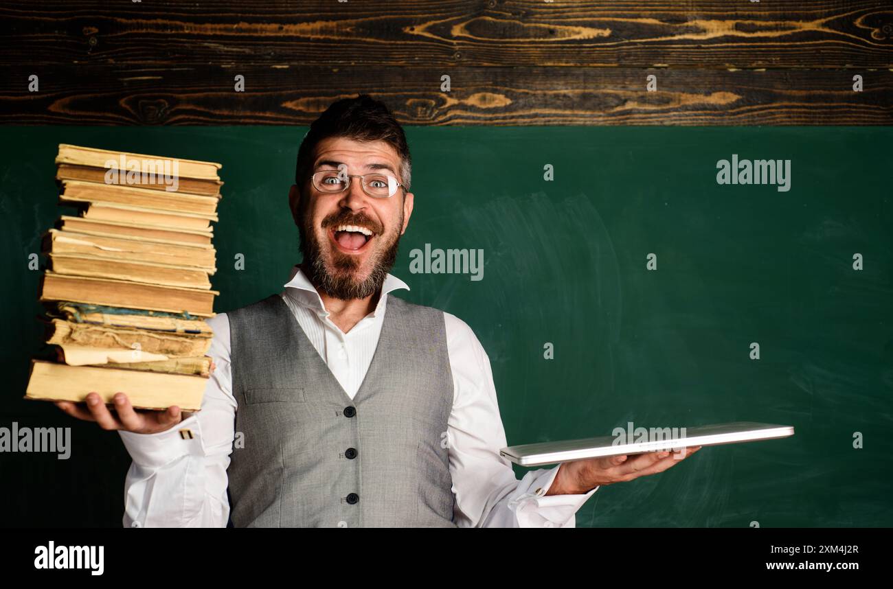 Male teacher with laptop and textbook in classroom. Modern education ...