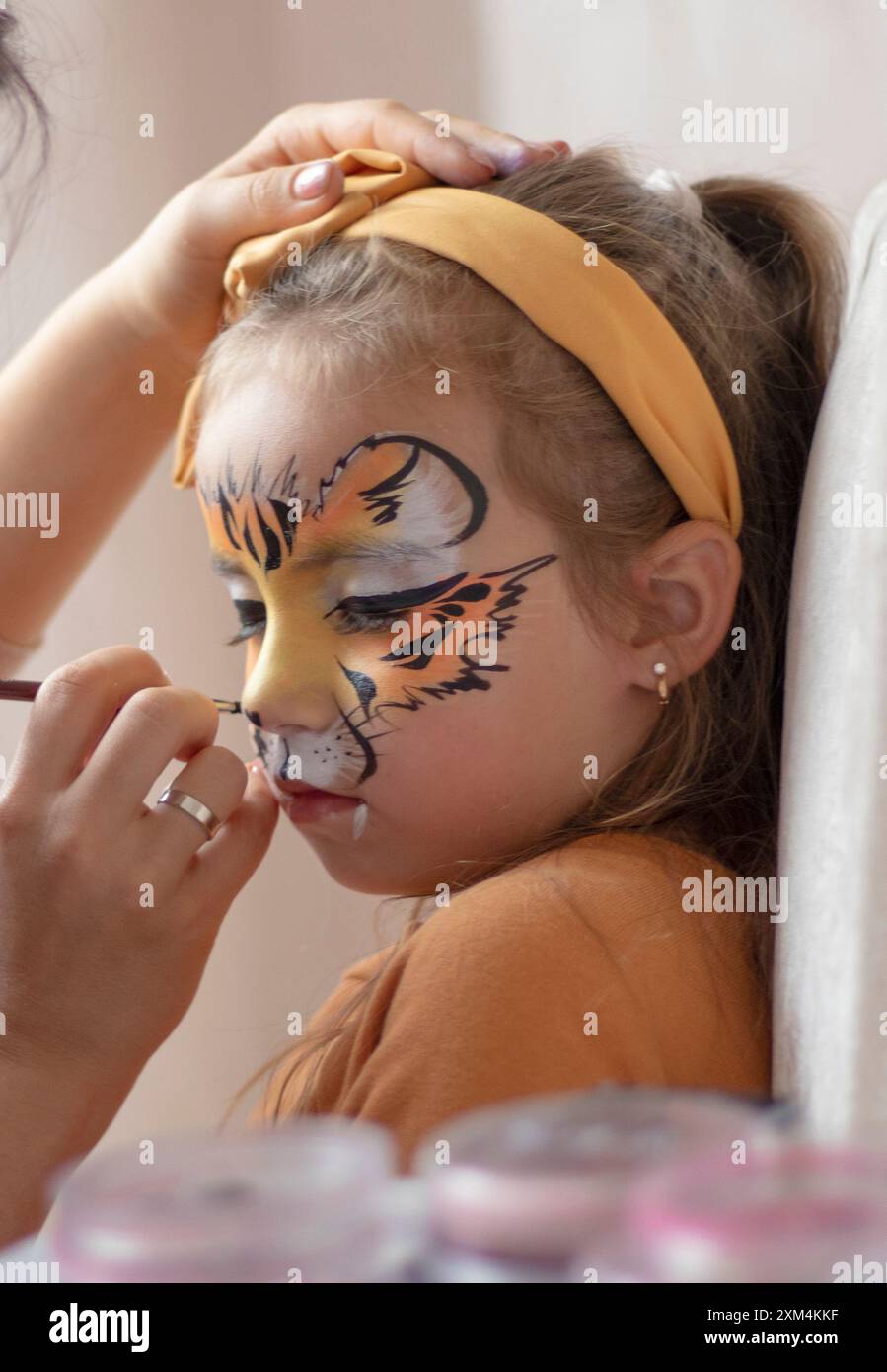 Cute makeup little tiger. girl getting face painting outdoors Stock ...