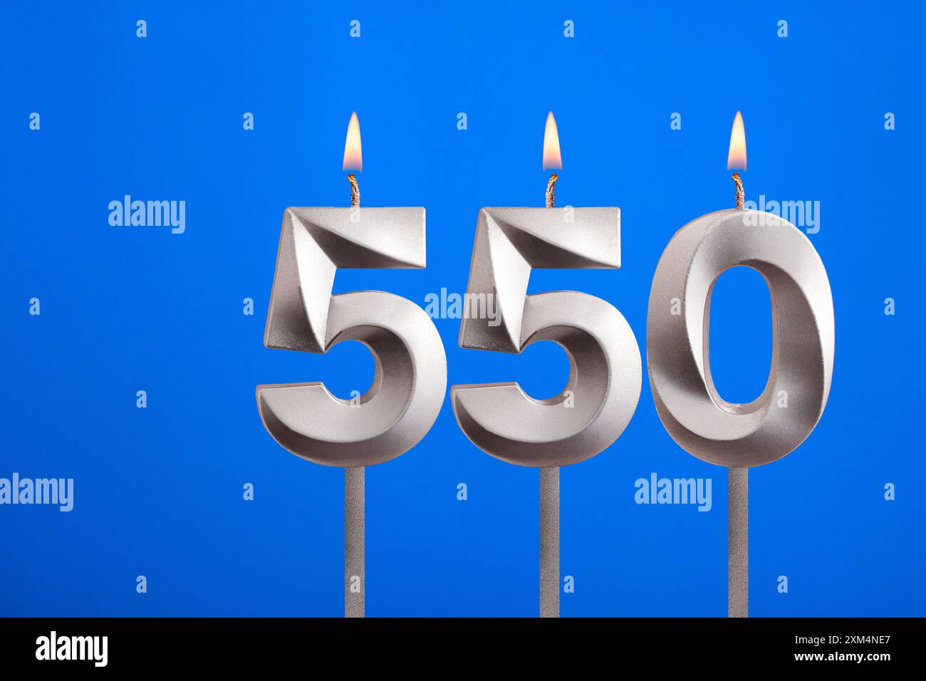 Birthday number 550 - Candle lit on blue background Stock Photo - Alamy