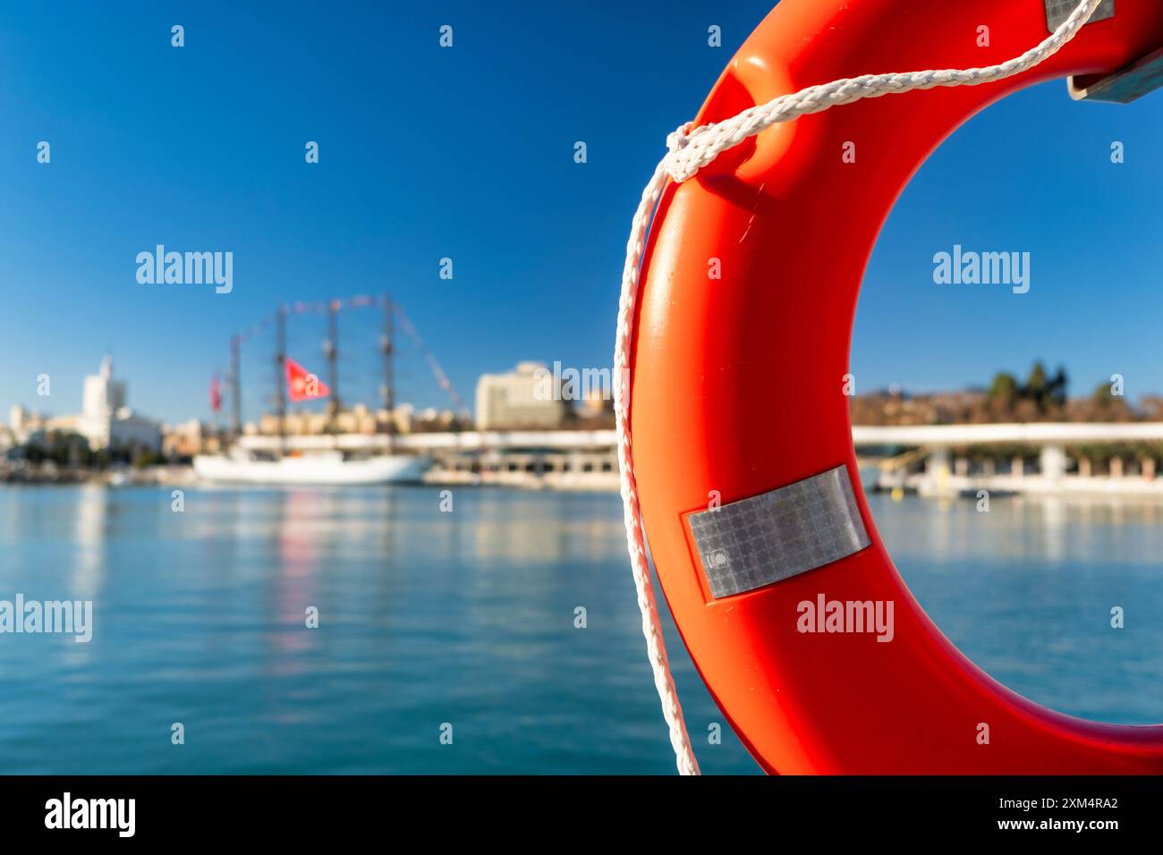 Vibrant orange lifebuoy dominates the foreground in a peaceful marina ...