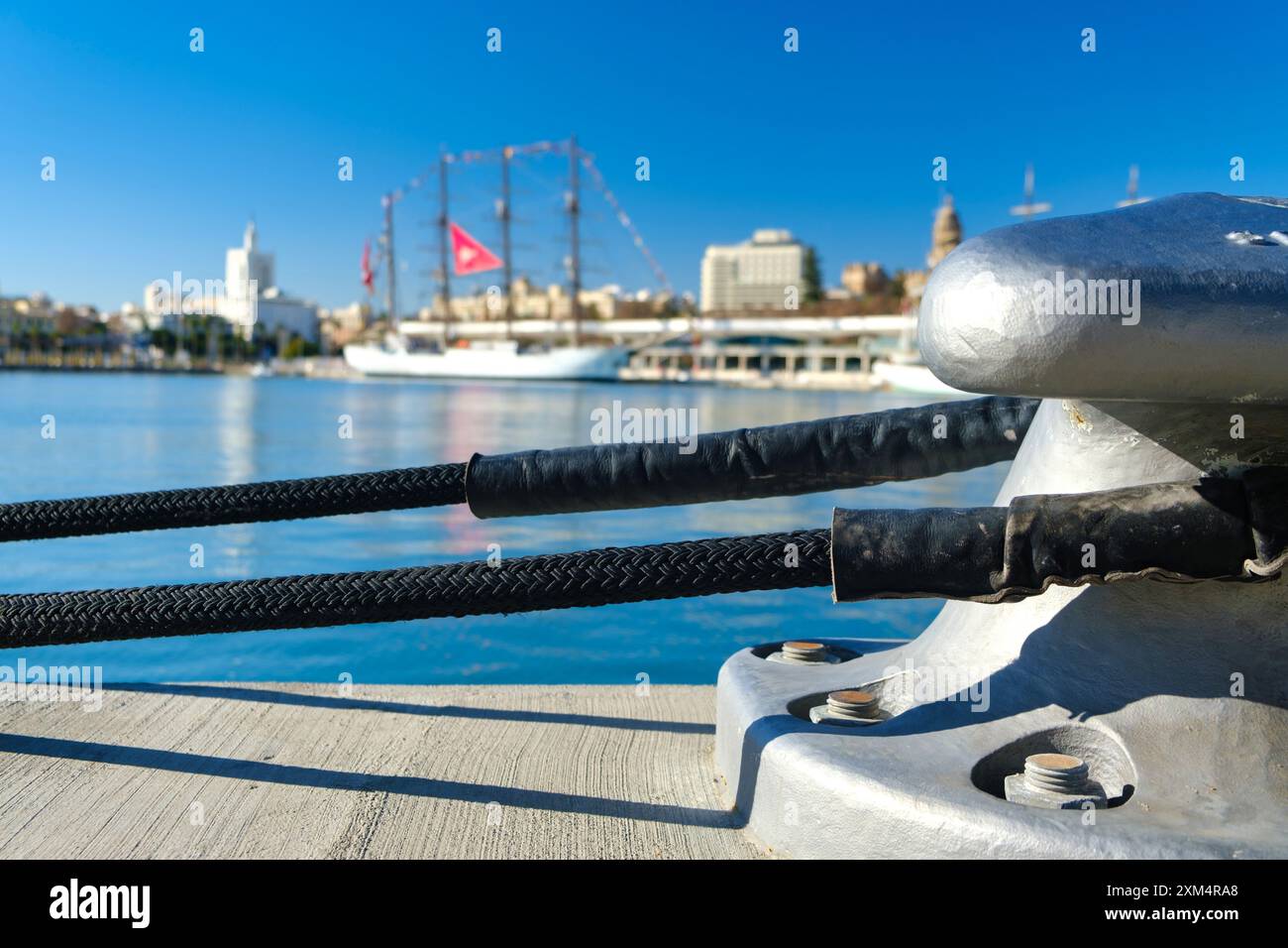 Close-up of metallic bollard with black ropes at Turkish dock under ...