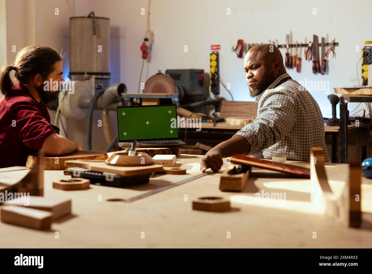 Carpenter talking with client about commissioned furniture assembling job, presenting on mockup ...