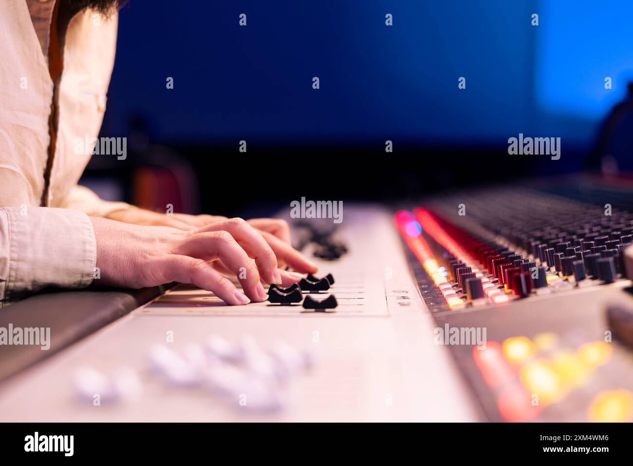 Music producer pushing faders and sliders on control panel board in ...