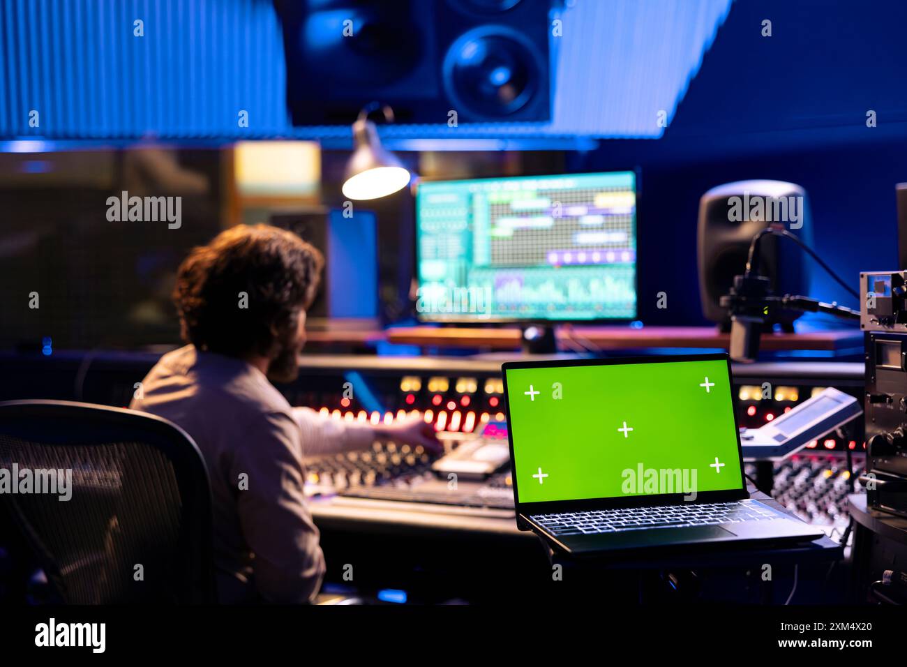 Sound engineer working on control desk with greenscreen layout in ...