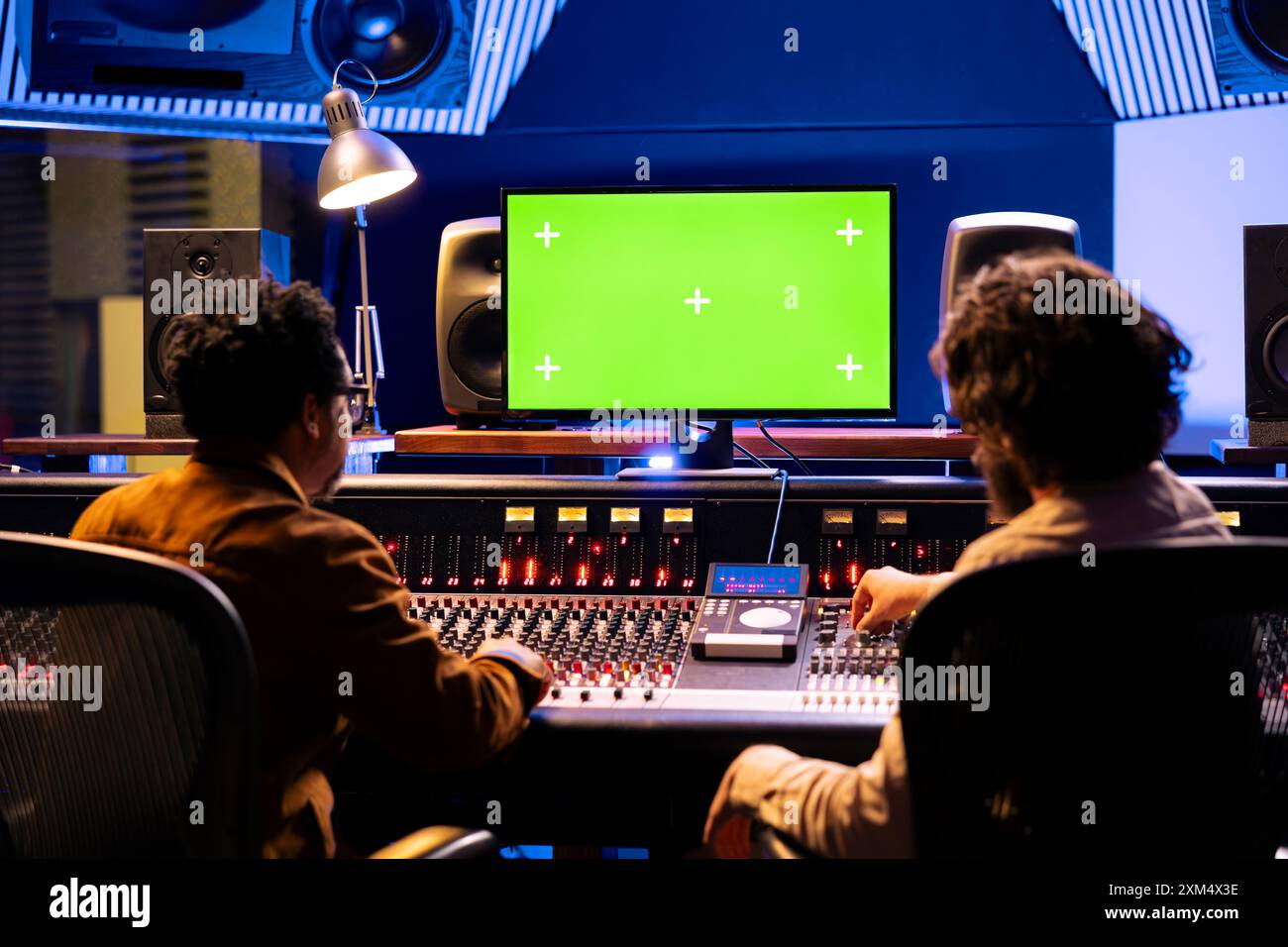 Team of musicians editing music with greenscreen on computer in ...