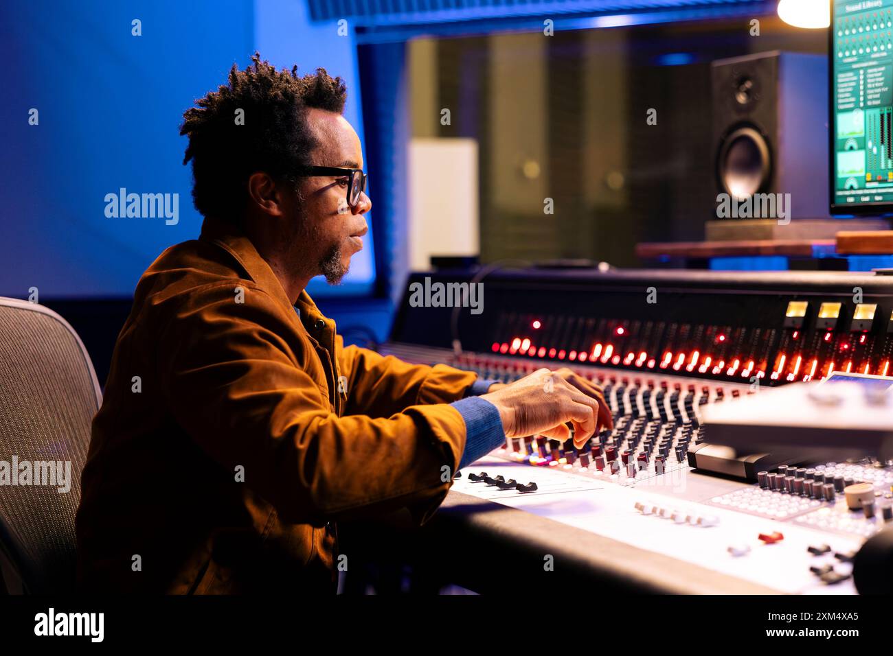 Music producer operating audio console in control room with ...