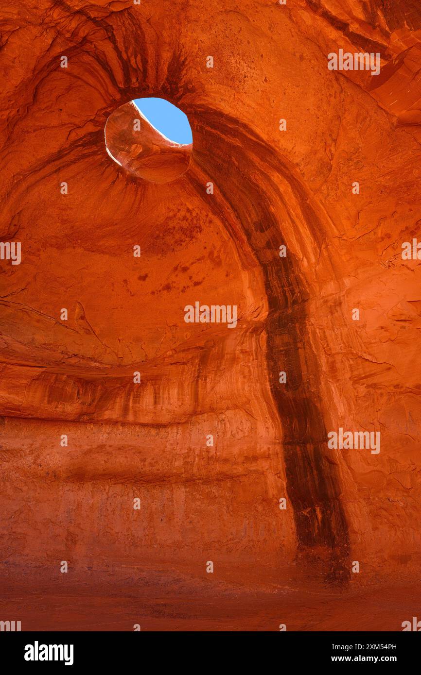 Sandstone rock formation with round opening and blue sky of Big Hogan ...