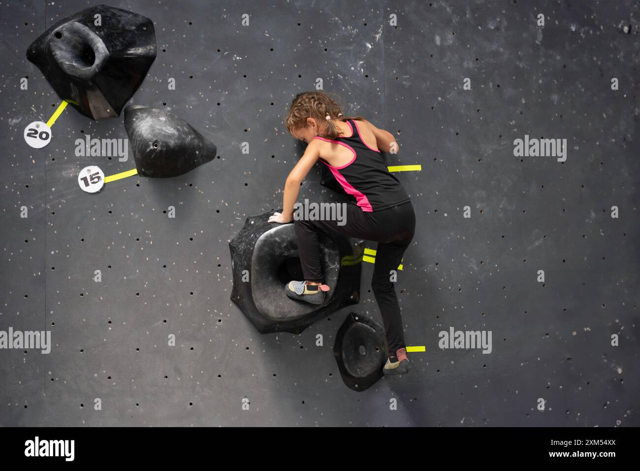 Determined little girl climbing artificial wall. Brave and strong ...