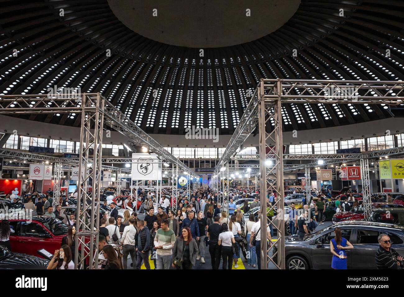 This photograph captures a bustling crowd at a car dealership event in ...