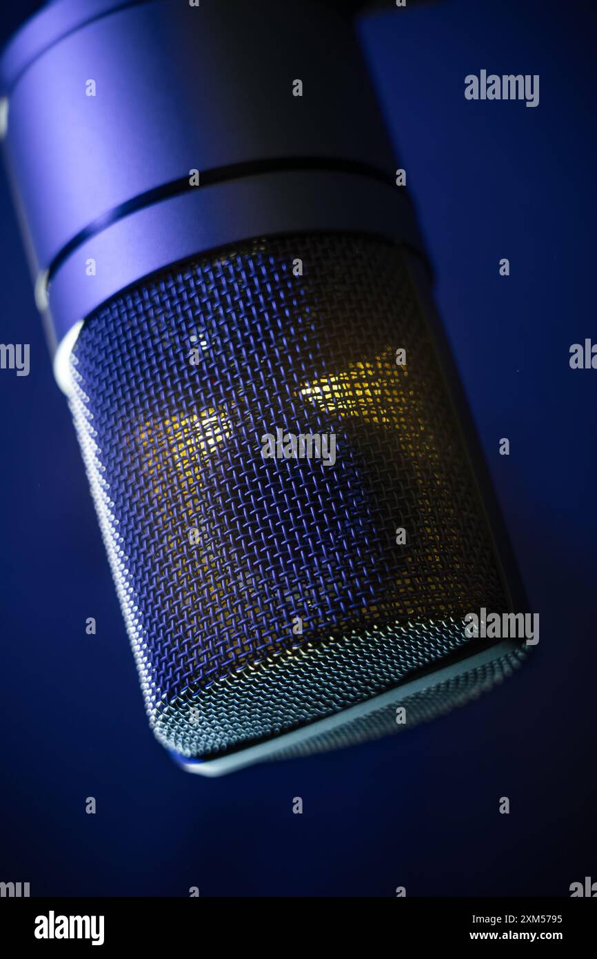 Retro microphone with detailed mesh grill illuminated by blue and ...