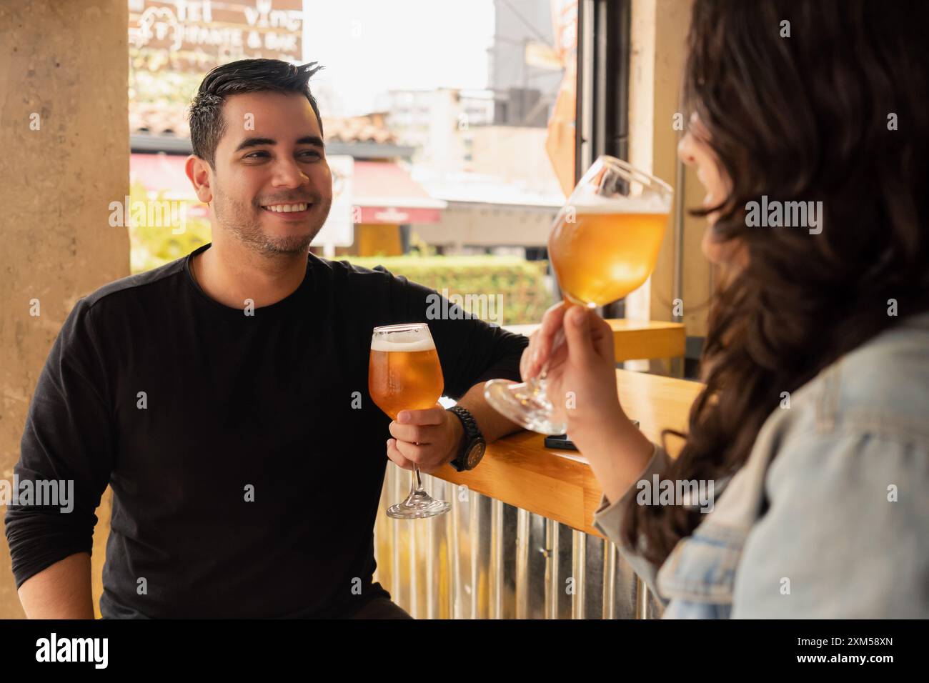 Smiling young man and woman enjoying a refreshing glass of beer at a ...