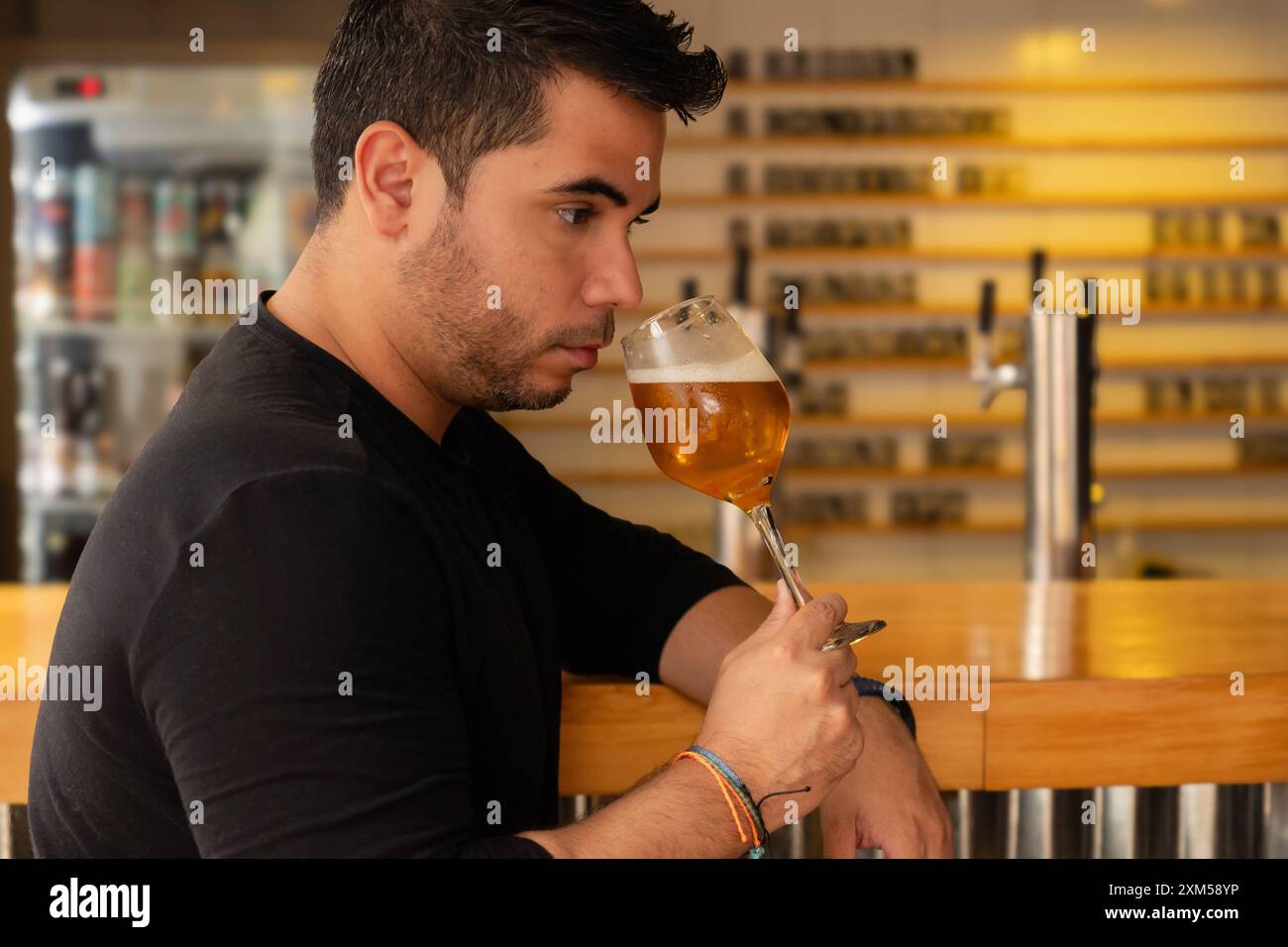 Close-up of a young Latino man sipping a beer in a nightclub with a ...