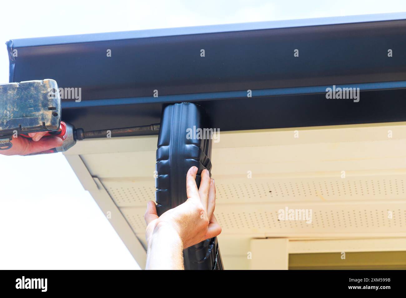 Installing rain gutter on roof, fitting downpipe, downspout bend Stock ...