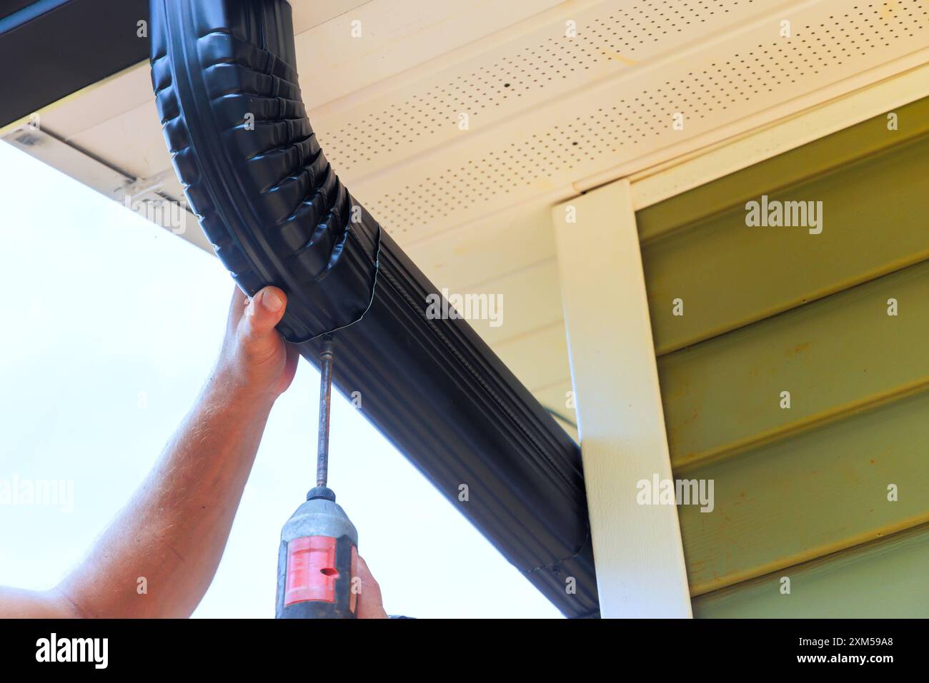 During installation of rain gutters on roofs, worker is fitting ...