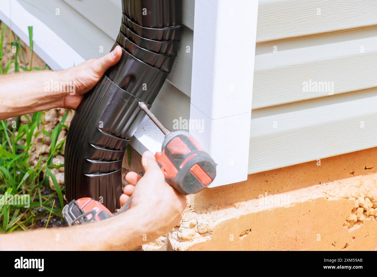 Installing rain gutter on roof with an professional is fitting downpipe ...