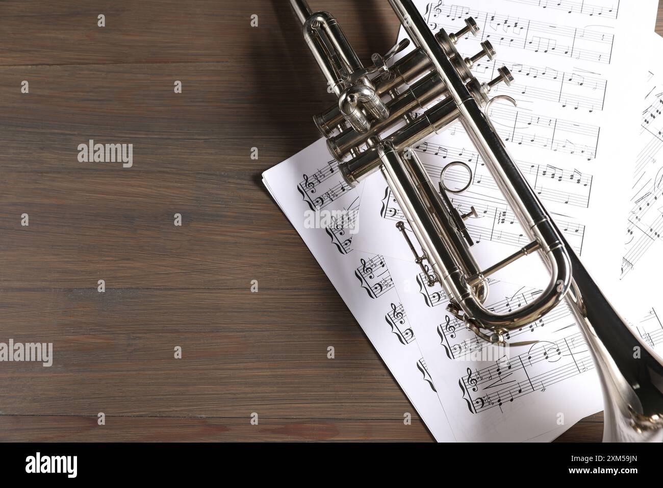 Trumpet and music sheet papers with notes on wooden table, top view ...