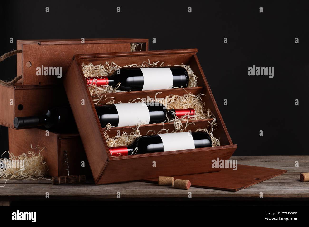 Box with wine bottles on wooden table against black background Stock ...