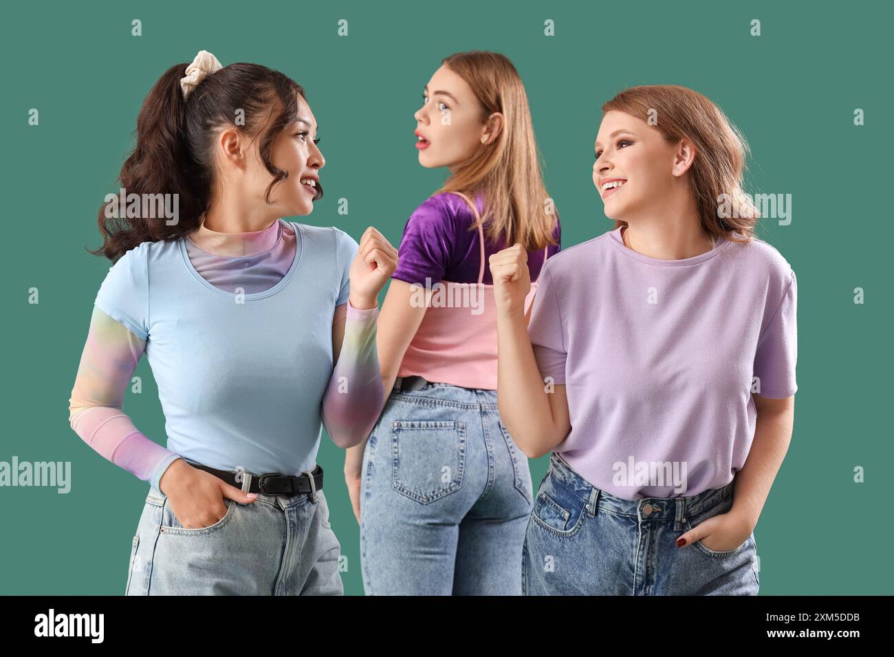 Young women gossiping behind friend's back on green background Stock ...