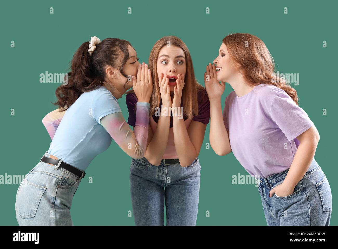 Young women gossiping on green background Stock Photo - Alamy