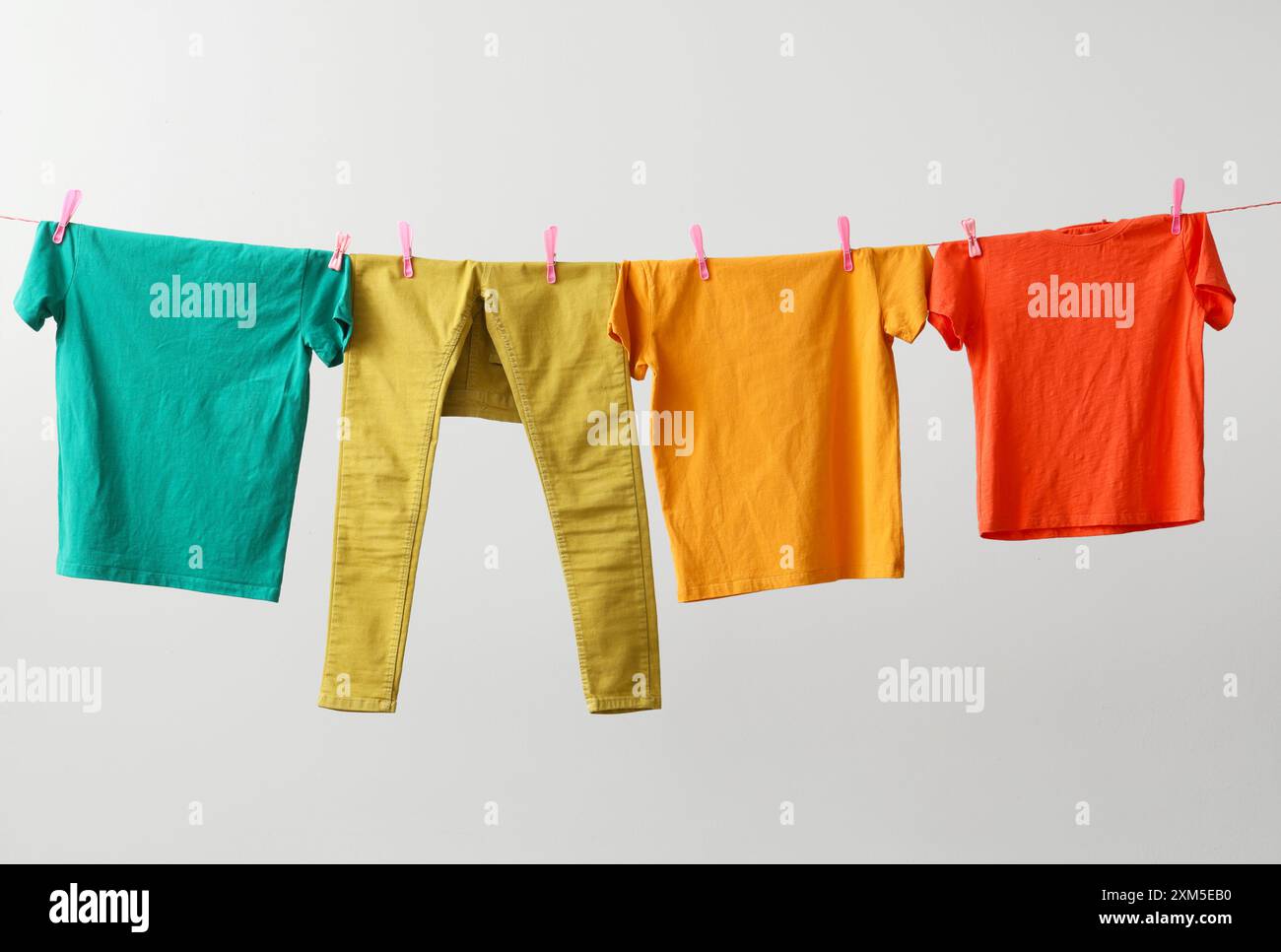 Different clean clothes hanging on rope against grey background Stock ...