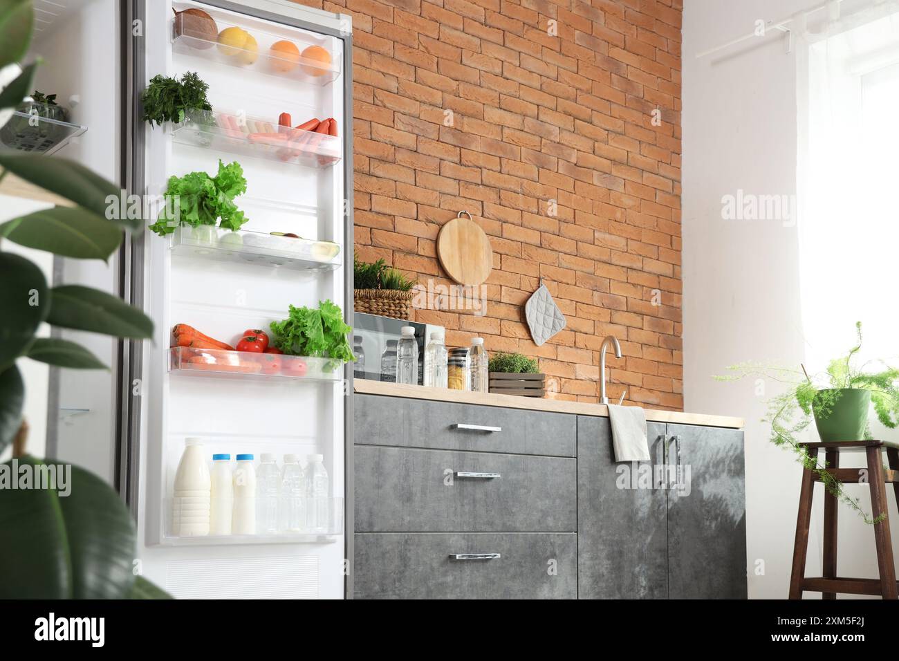 Open fridge full of fresh food near brown brick wall in kitchen Stock ...