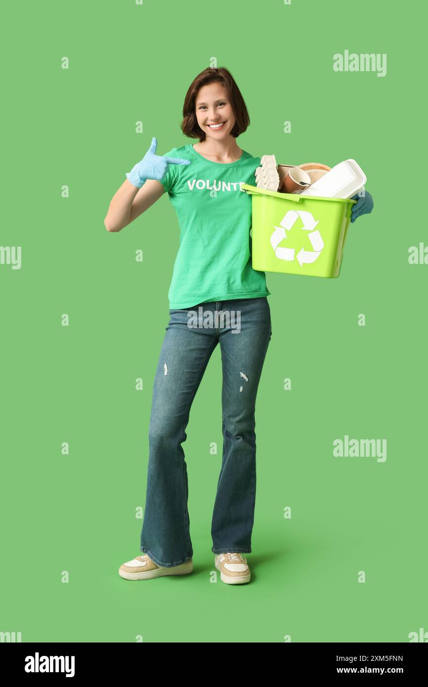 Female volunteer pointing at recycle bin with garbage on green ...