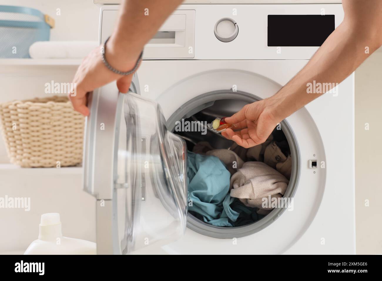 Man putting capsule of detergent into washing machine in laundry room ...