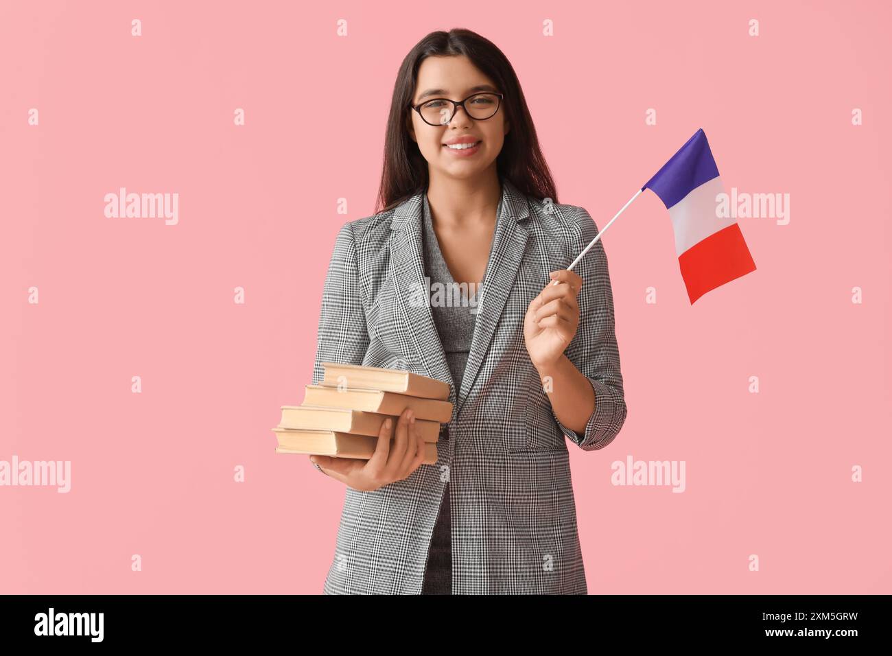 Female French language teacher with books and flag on pink background ...