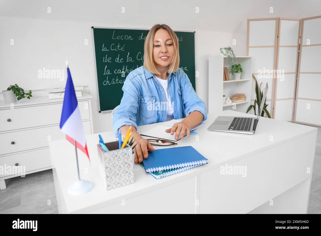 Female French language teacher working with notebook at table in ...