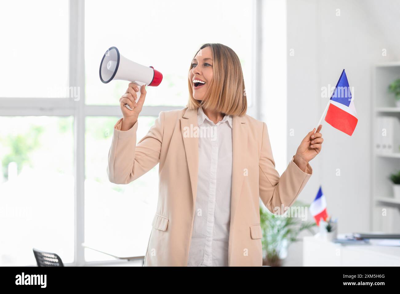 Female French language teacher with flag and megaphone in light ...