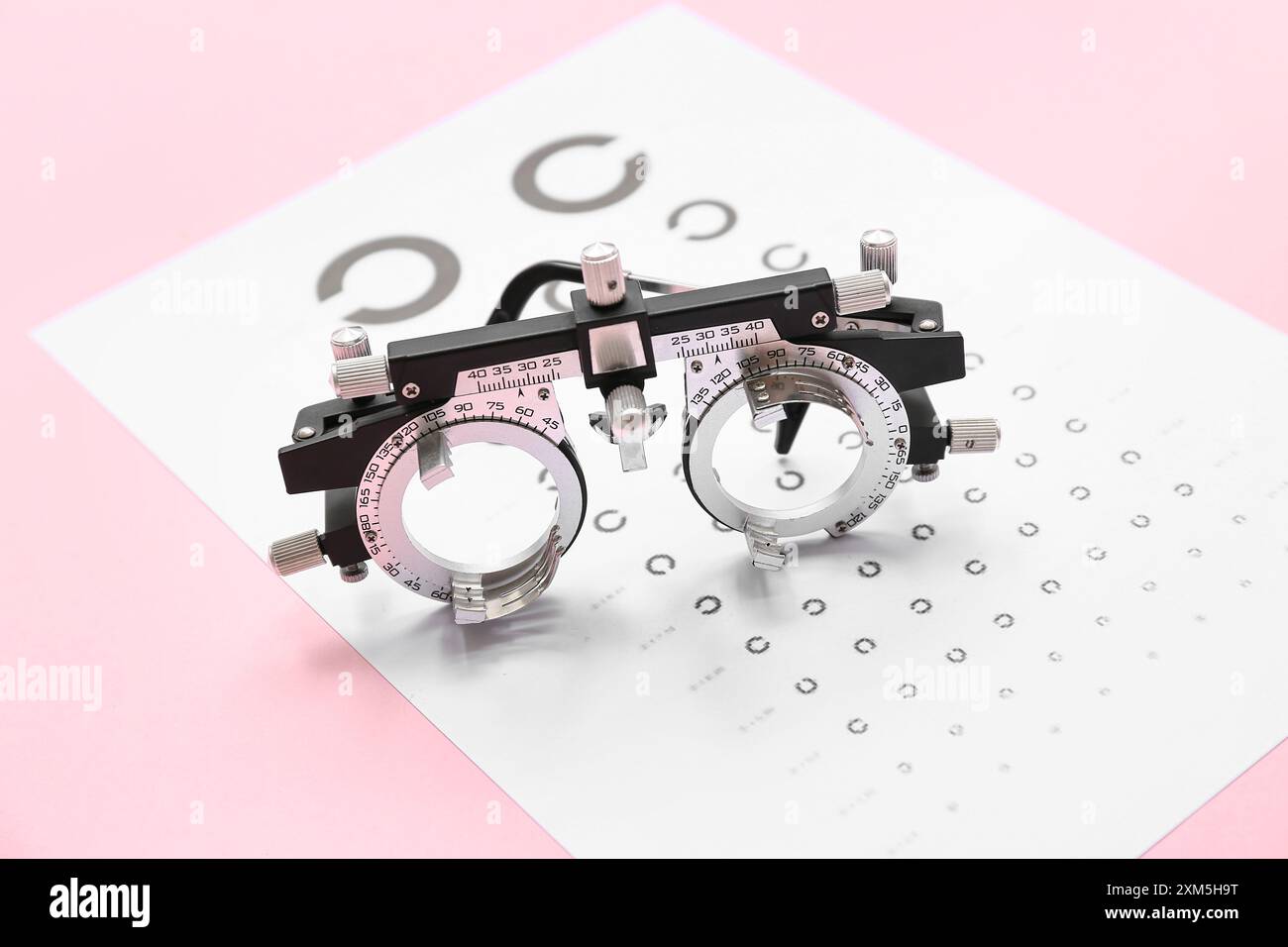 Optical trial frame with eye test chart on pink background Stock Photo ...