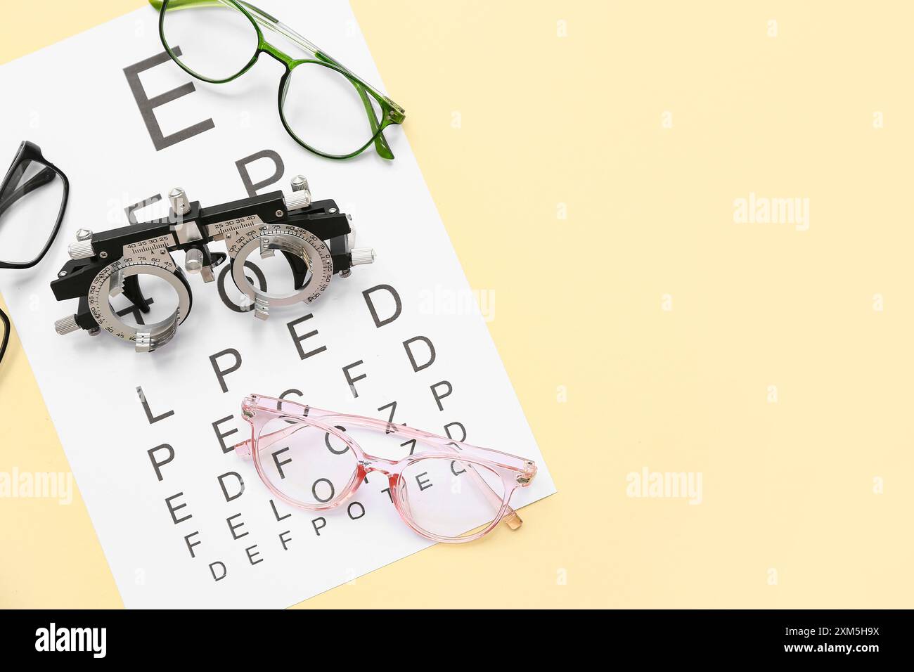 Optical trial frame with eye test chart and eyeglasses on pink ...