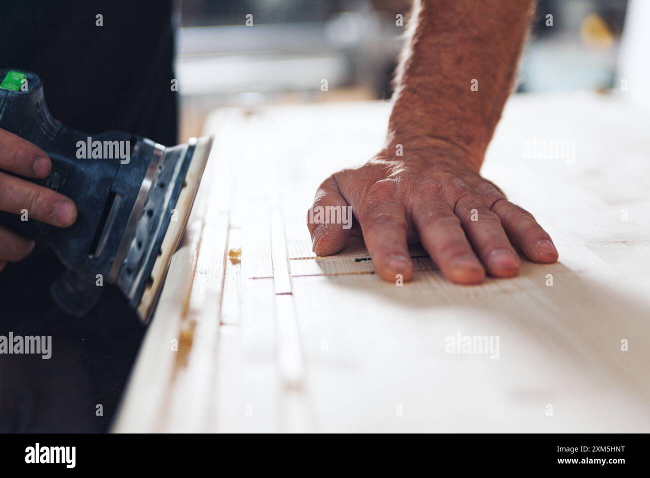 Skilled carpenter sanding wooden plank in workshop, showcasing ...