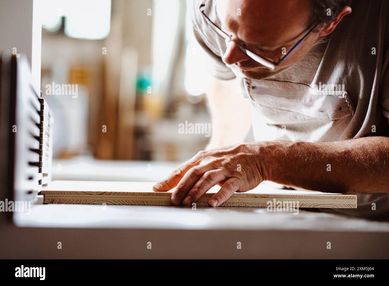 Carpenter meticulously inspecting a wood plank in his workshop ...