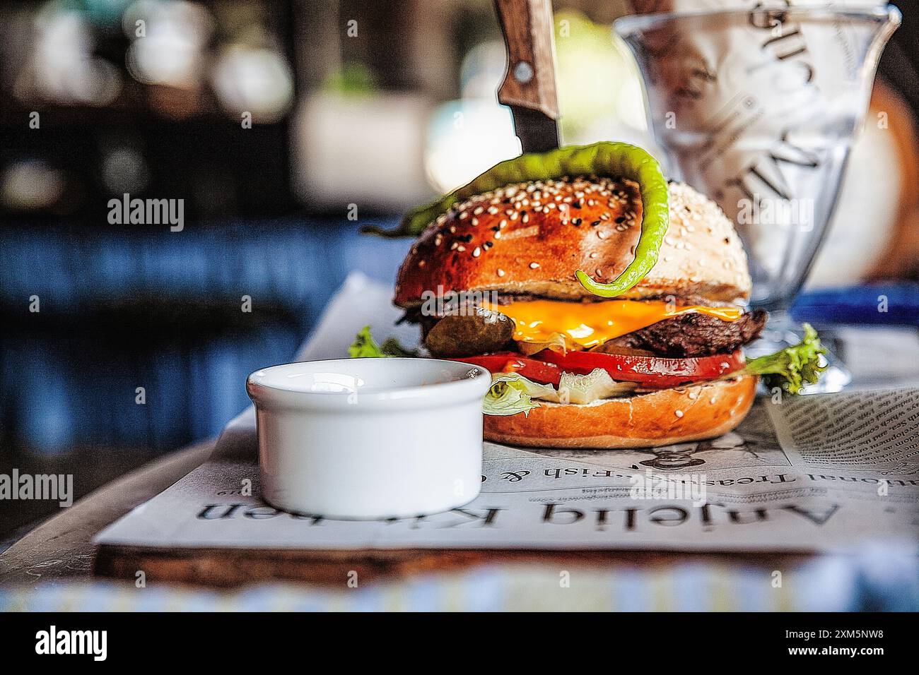Juicy burger with patty, cheese and green peppers with a stuck knife ...