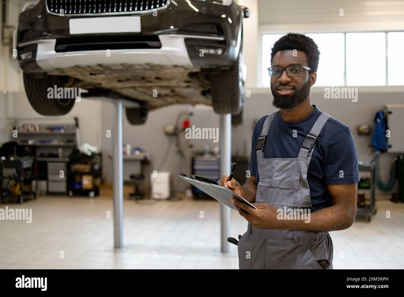 Mechanic inspecting car in auto repair shop with clipboard Stock Photo - Alamy