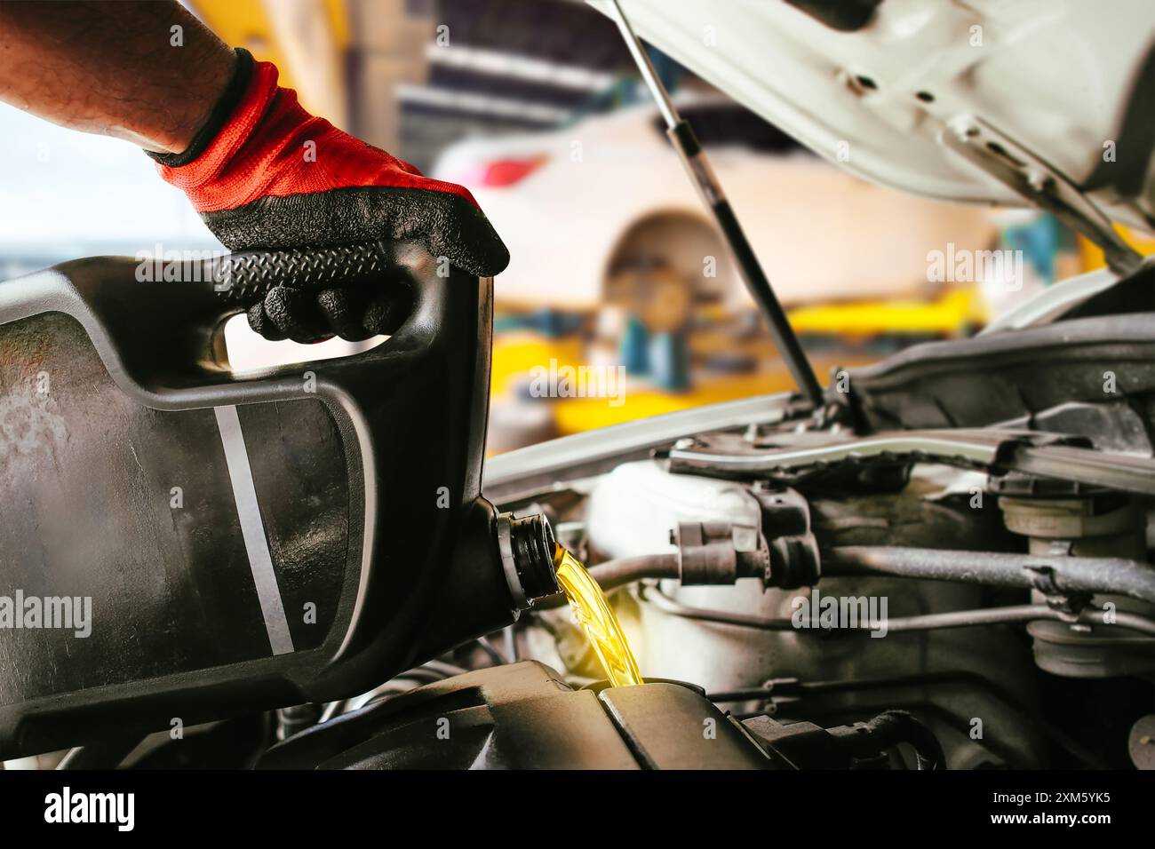 Car mechanic pouring engine oil into engine , mechanic is changing ...